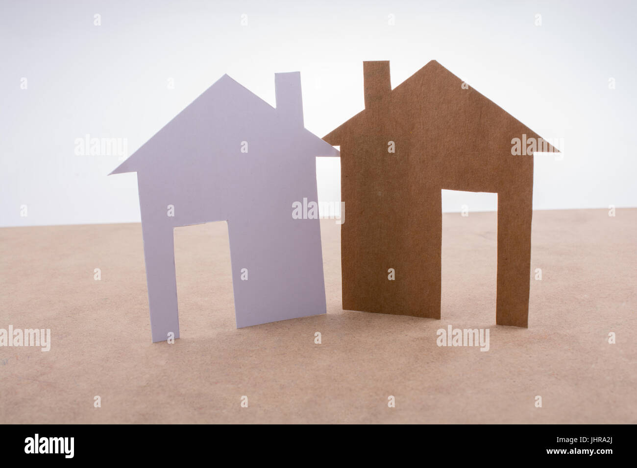 Little paper houses on a brown background Stock Photo - Alamy