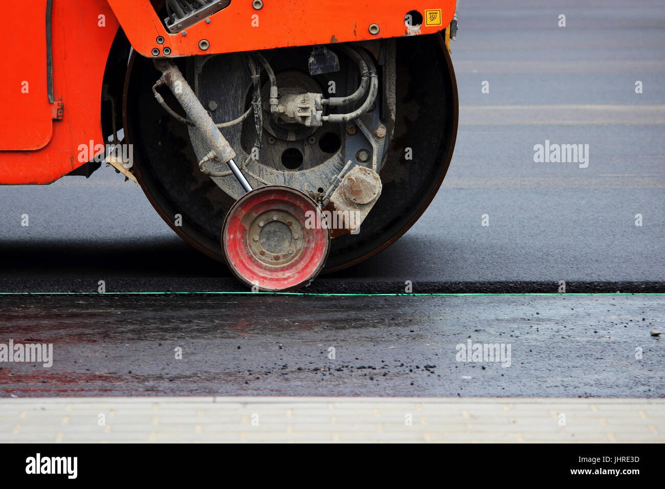 Heavy compactor tires the upper layer of asphalt in the construction of ...