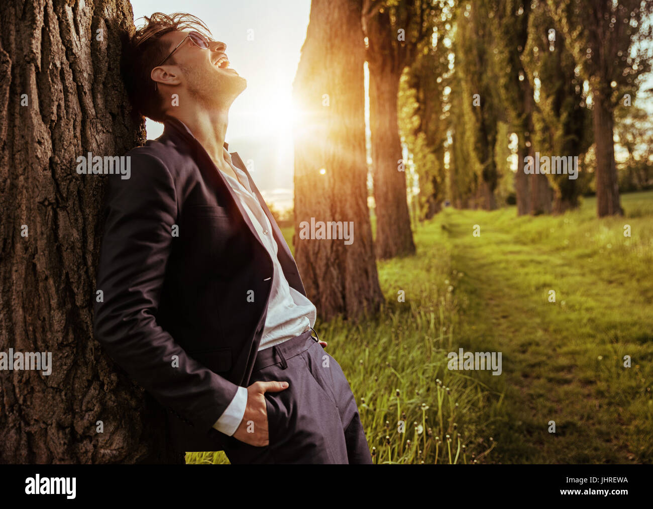 Calm, relaxed guy leaning on the tree Stock Photo - Alamy