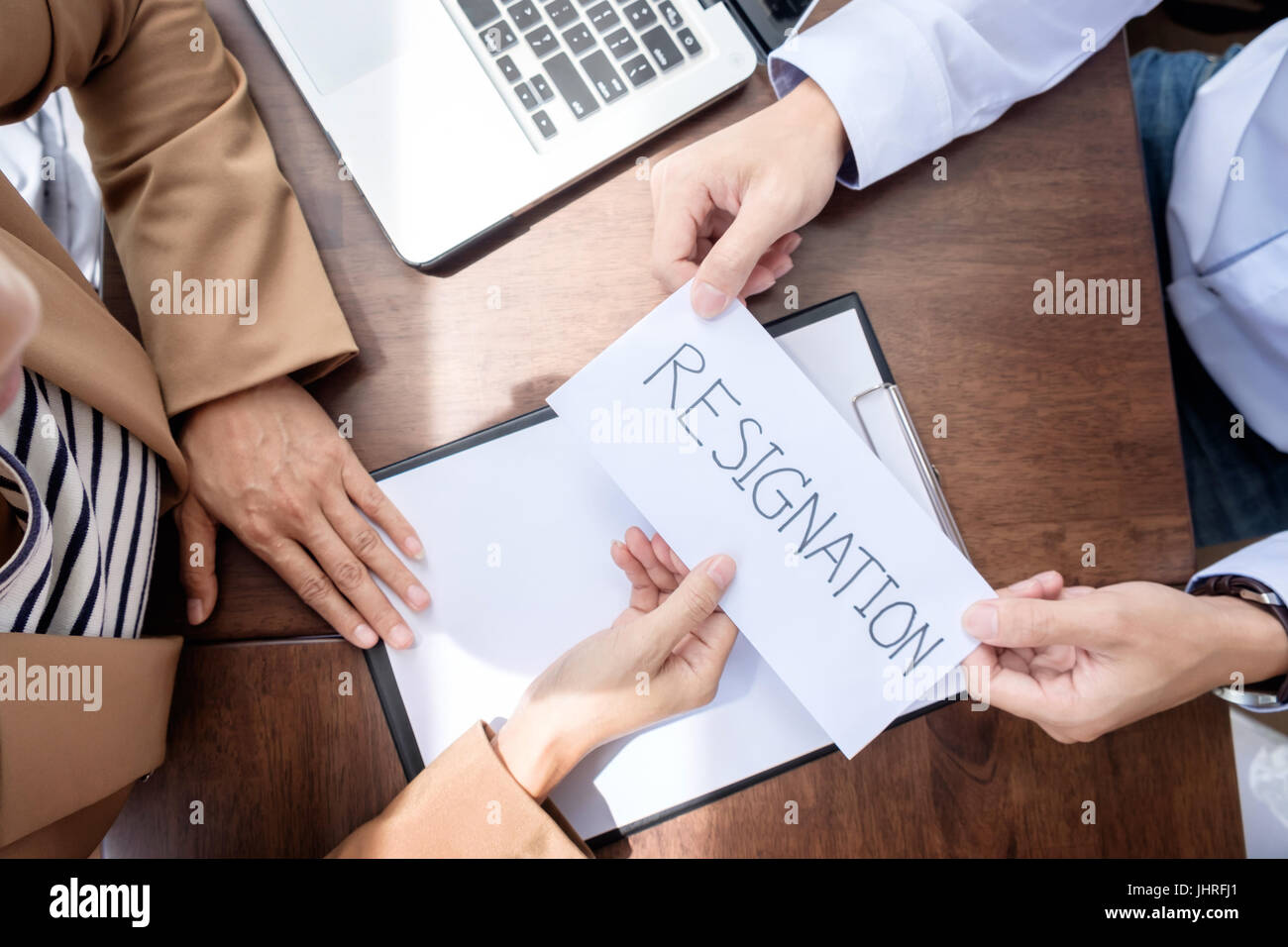 Hand of a businessman hands over a resignation letter on a wooden table ...