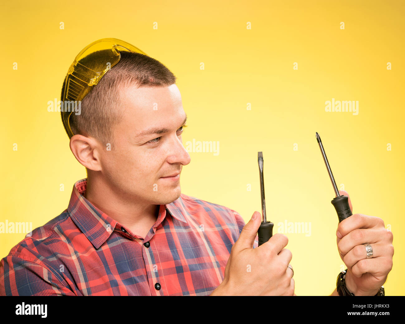 a man with a screwdriver on a yellow background Stock Photo - Alamy
