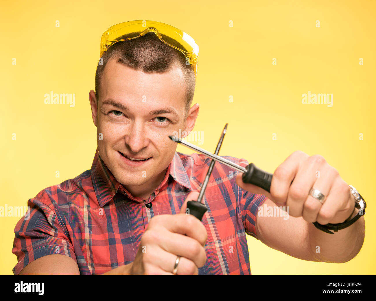 a man with a screwdriver on a yellow background Stock Photo - Alamy