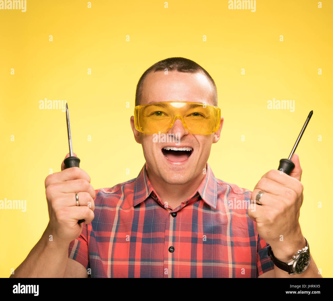 a man with a screwdriver on a yellow background Stock Photo - Alamy