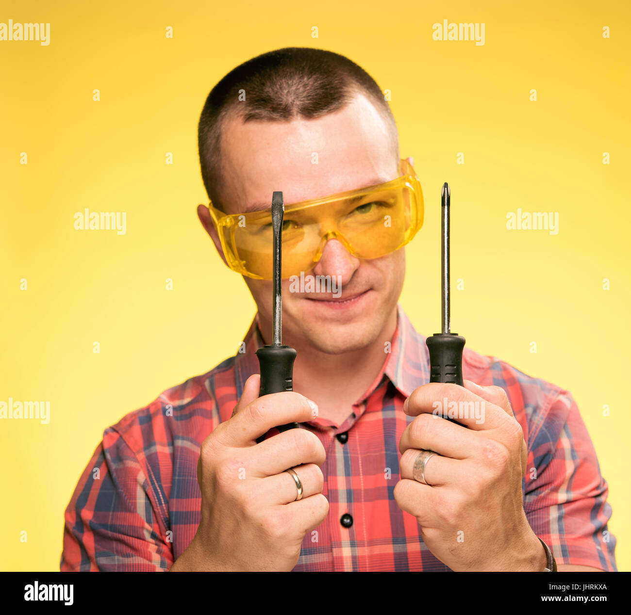 a man with a screwdriver on a yellow background Stock Photo - Alamy