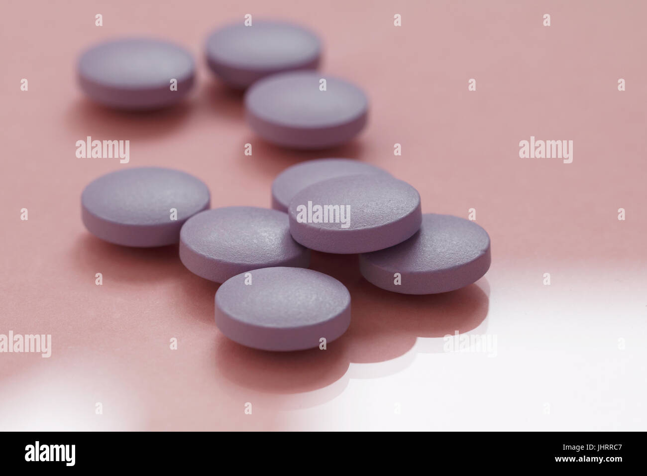 Close-up of purple pills on a pink background Stock Photo - Alamy