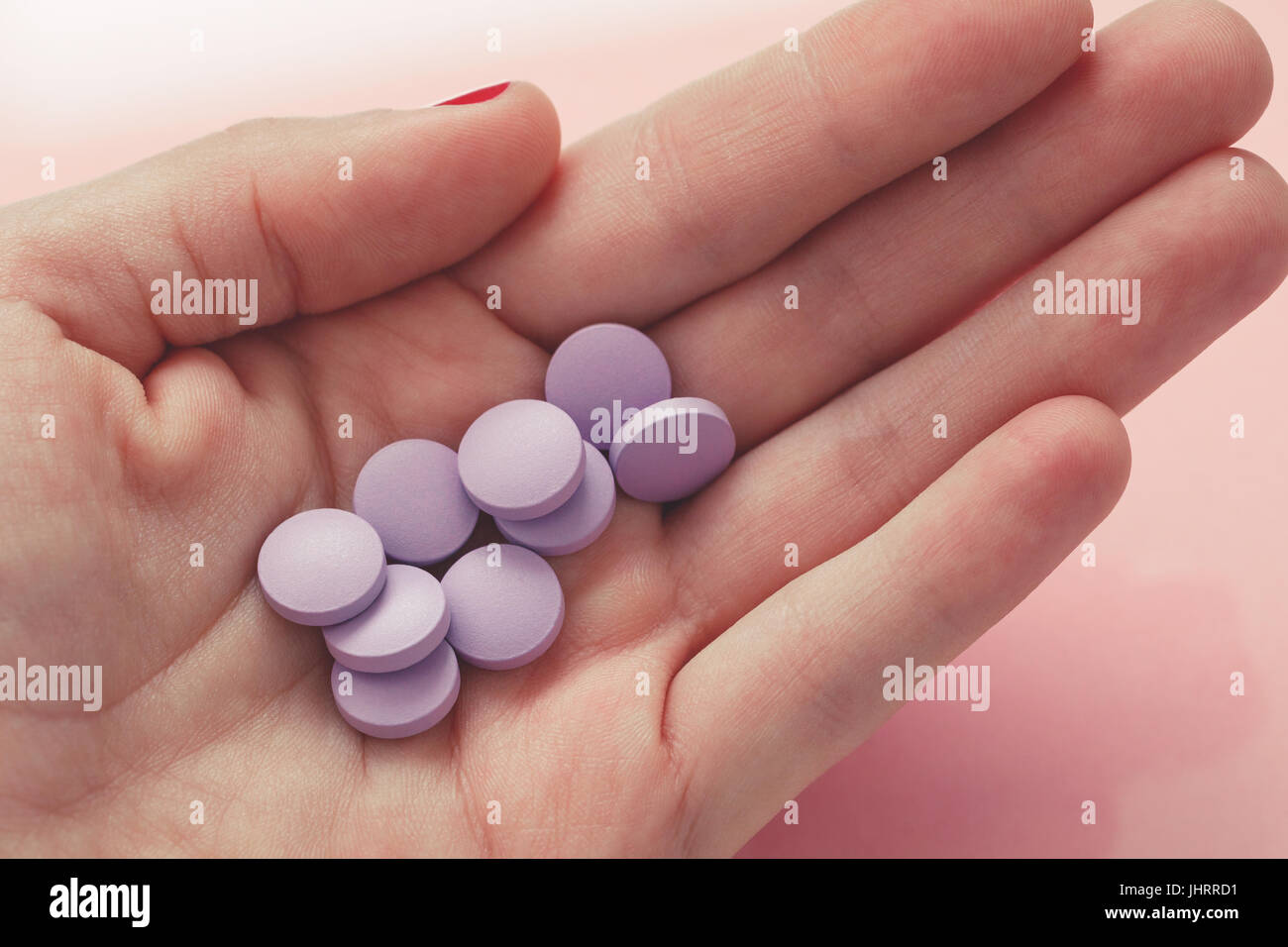 Purple tablets in the palm on a pink background. View from above Stock ...