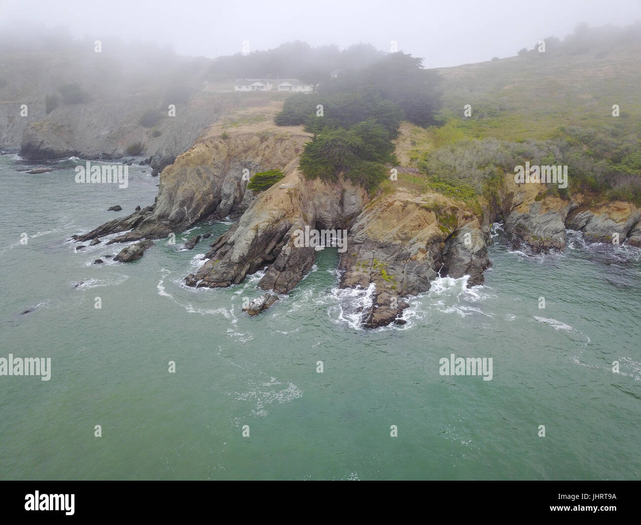 The cold waters of the Pacific Ocean washes against the mist-covered ...