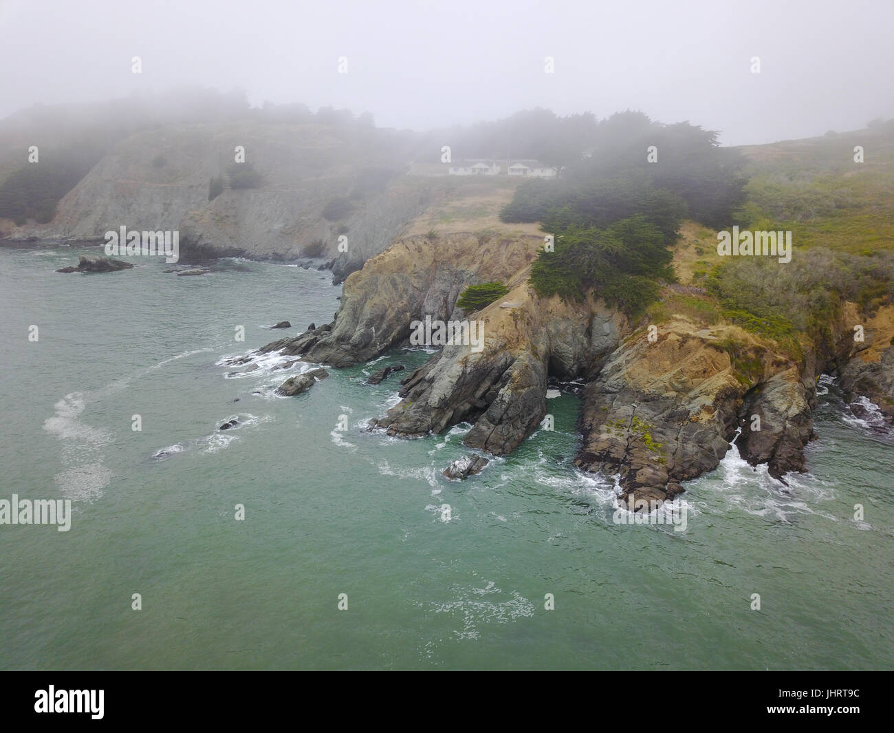 The cold waters of the Pacific Ocean washes against the mist-covered ...