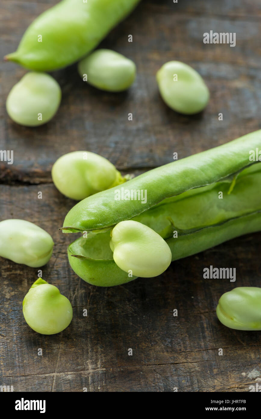 Fresh broad bean pods on wooden background - closeup with selective ...