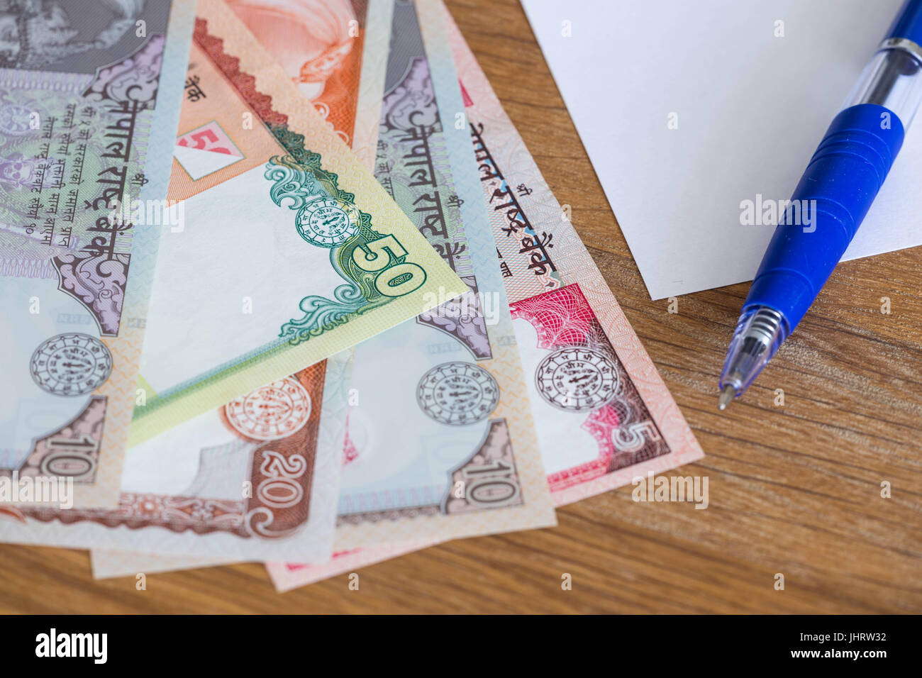 Nepal rupee money with a shett of paper and a pen for calculations ...