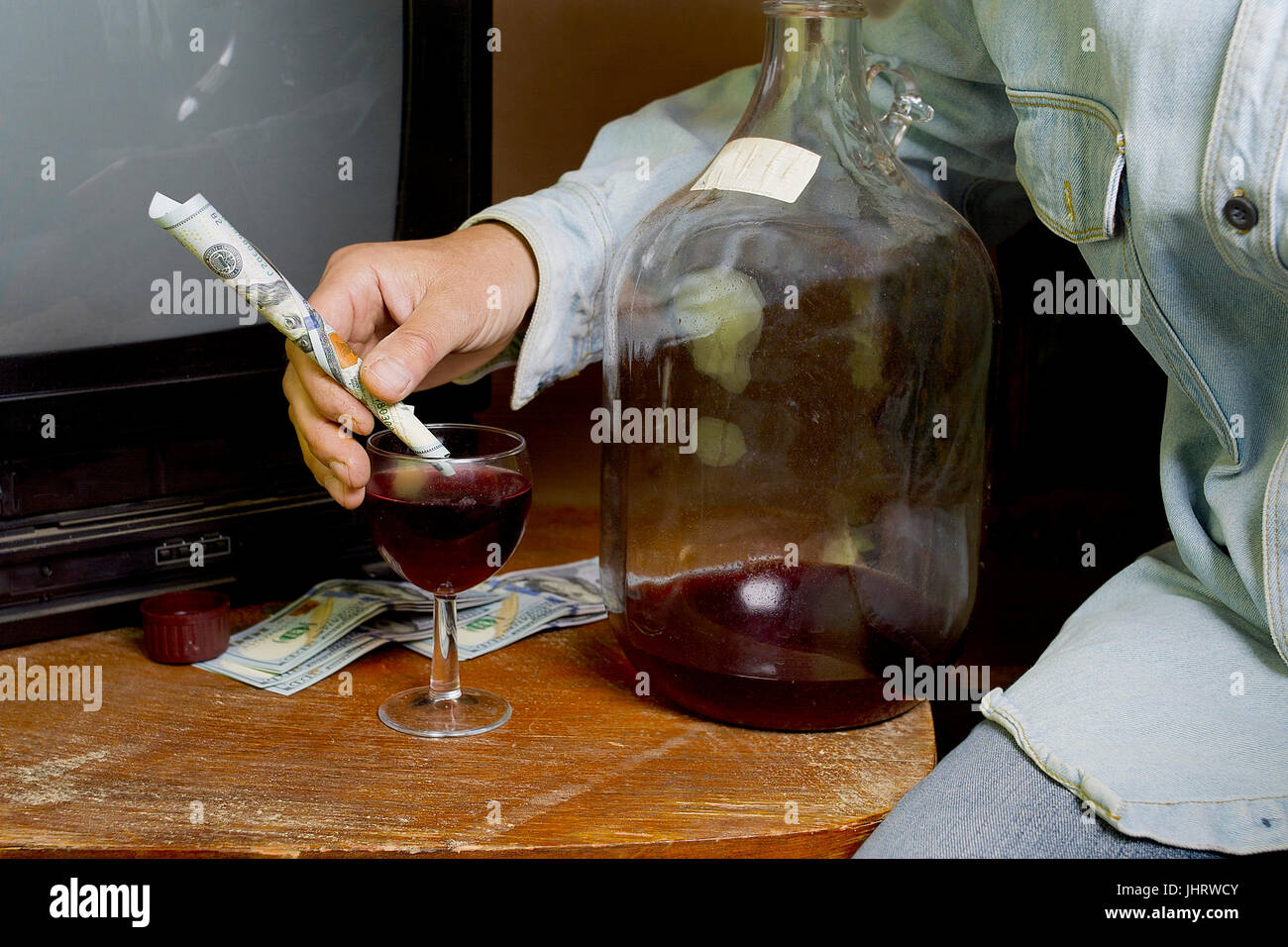 Human hand holding a straw made of a hundred dollar banknote, indoor ...