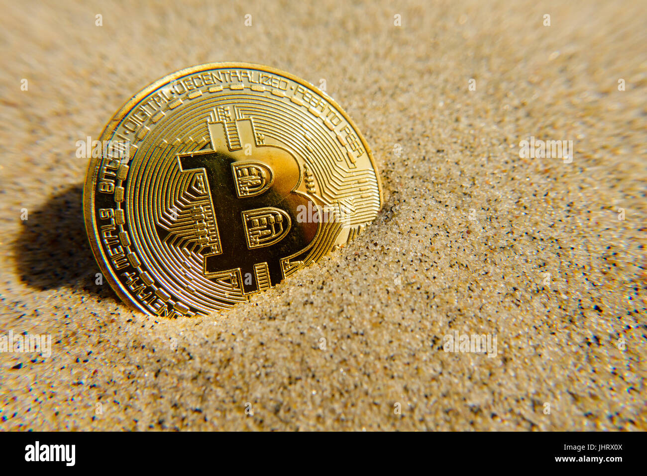Golden bitcoin coin is in the sand Stock Photo - Alamy