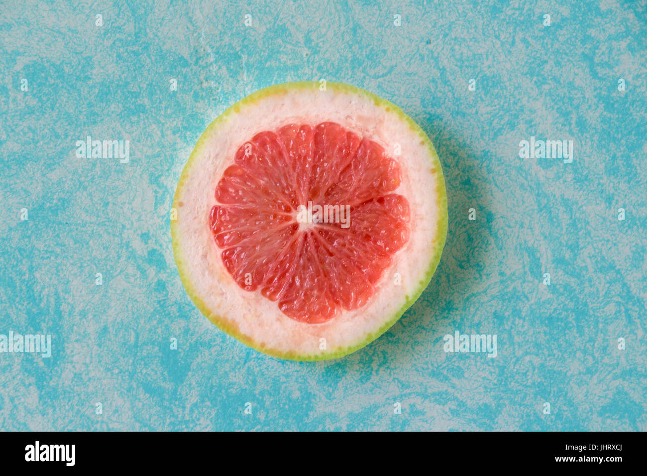 Photograph of a grapefruit slice on light blue background Stock Photo ...