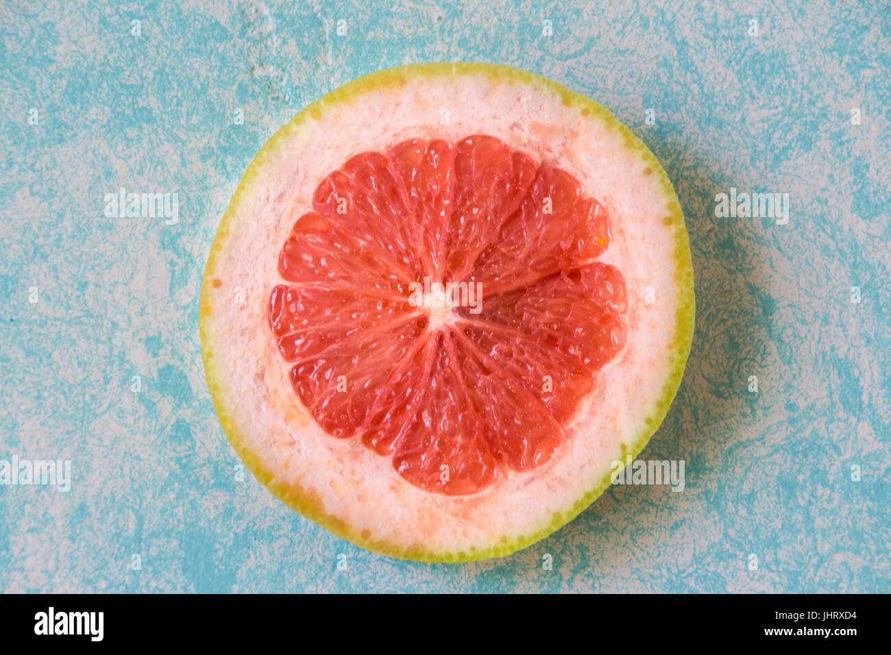 Photograph of a grapefruit slice on light blue background Stock Photo ...