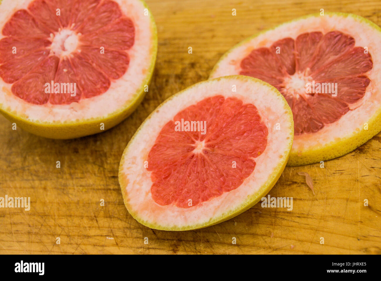 Photograph of some grapefruit slices on wood cutting board Stock Photo ...