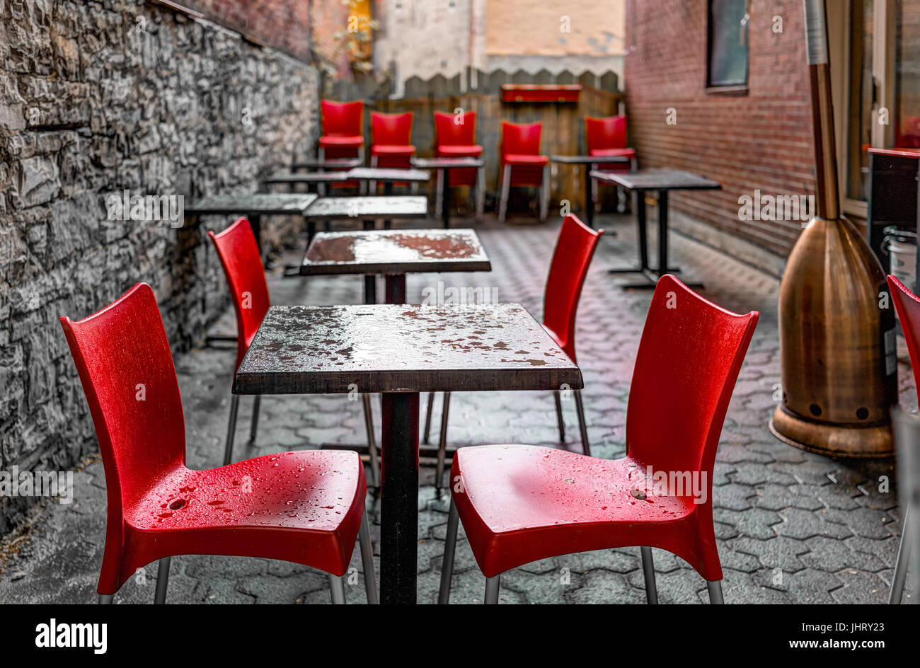 Wet tables outside restaurant by sidewalk with cobblestone European ...