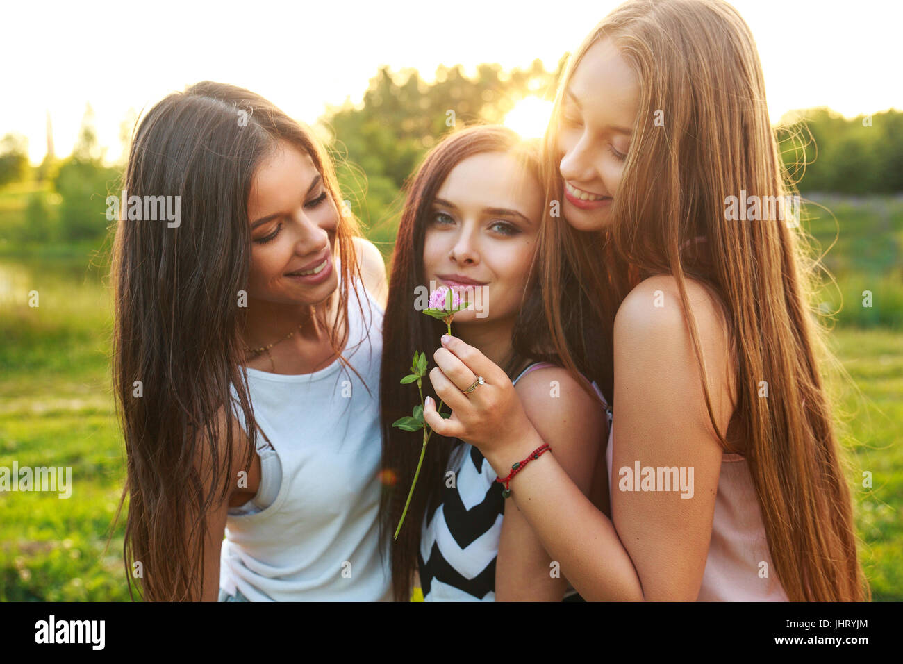 three women hugging each other outdoors and laughing on sunset ...