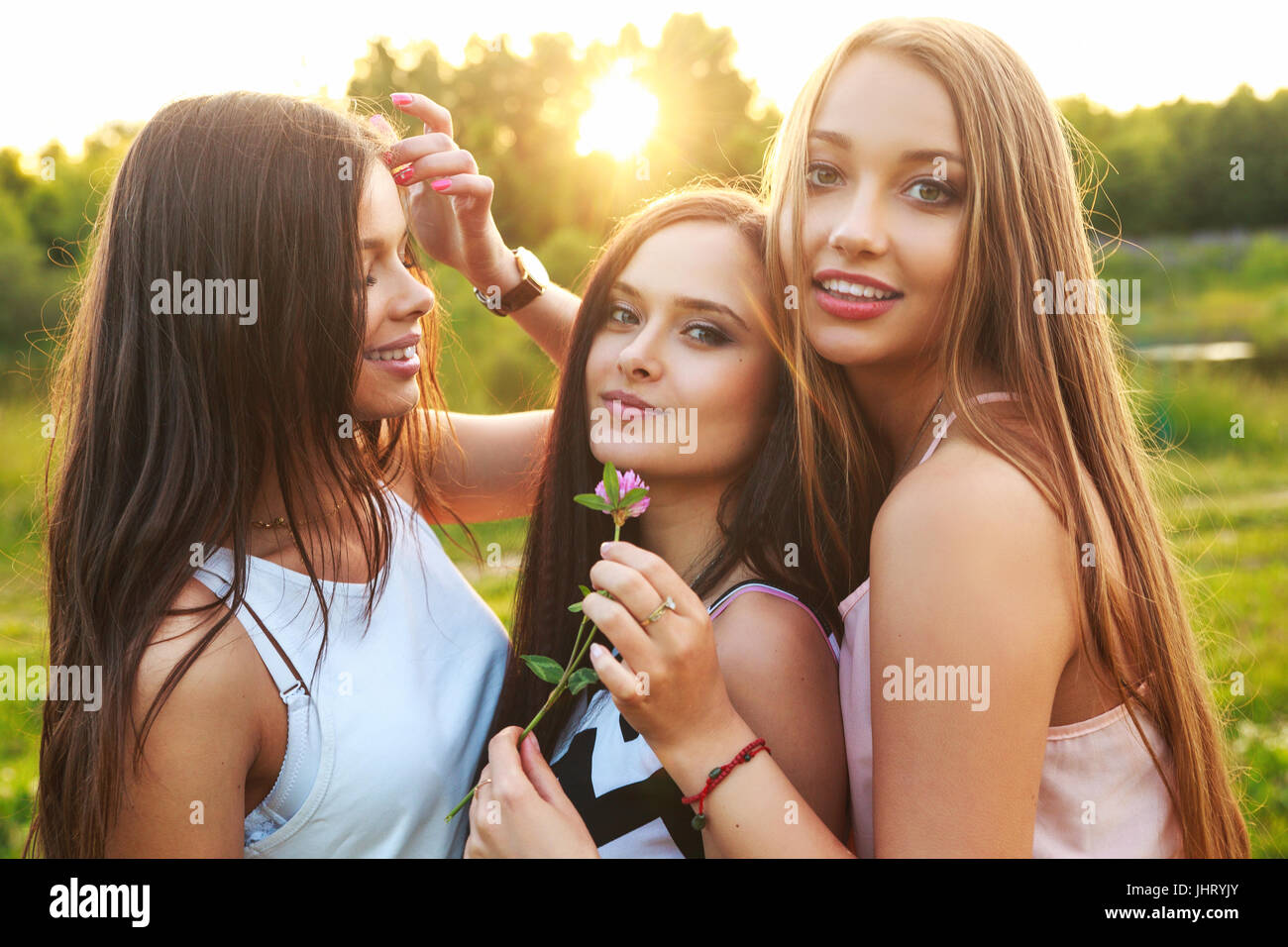 three women hugging each other outdoors and laughing on sunset ...