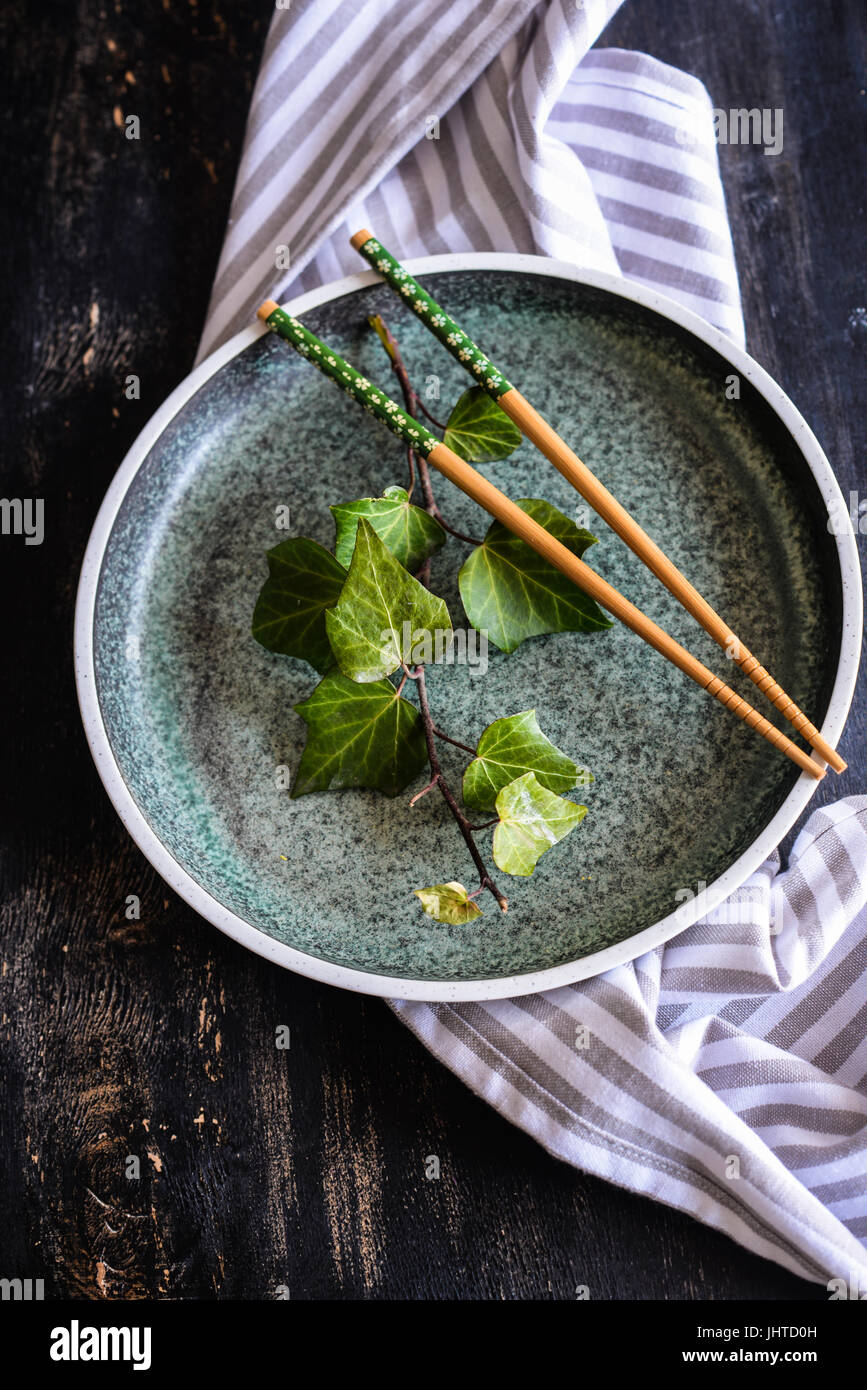Rustic table setting with wild grape leaves on the plate on dark wooden ...