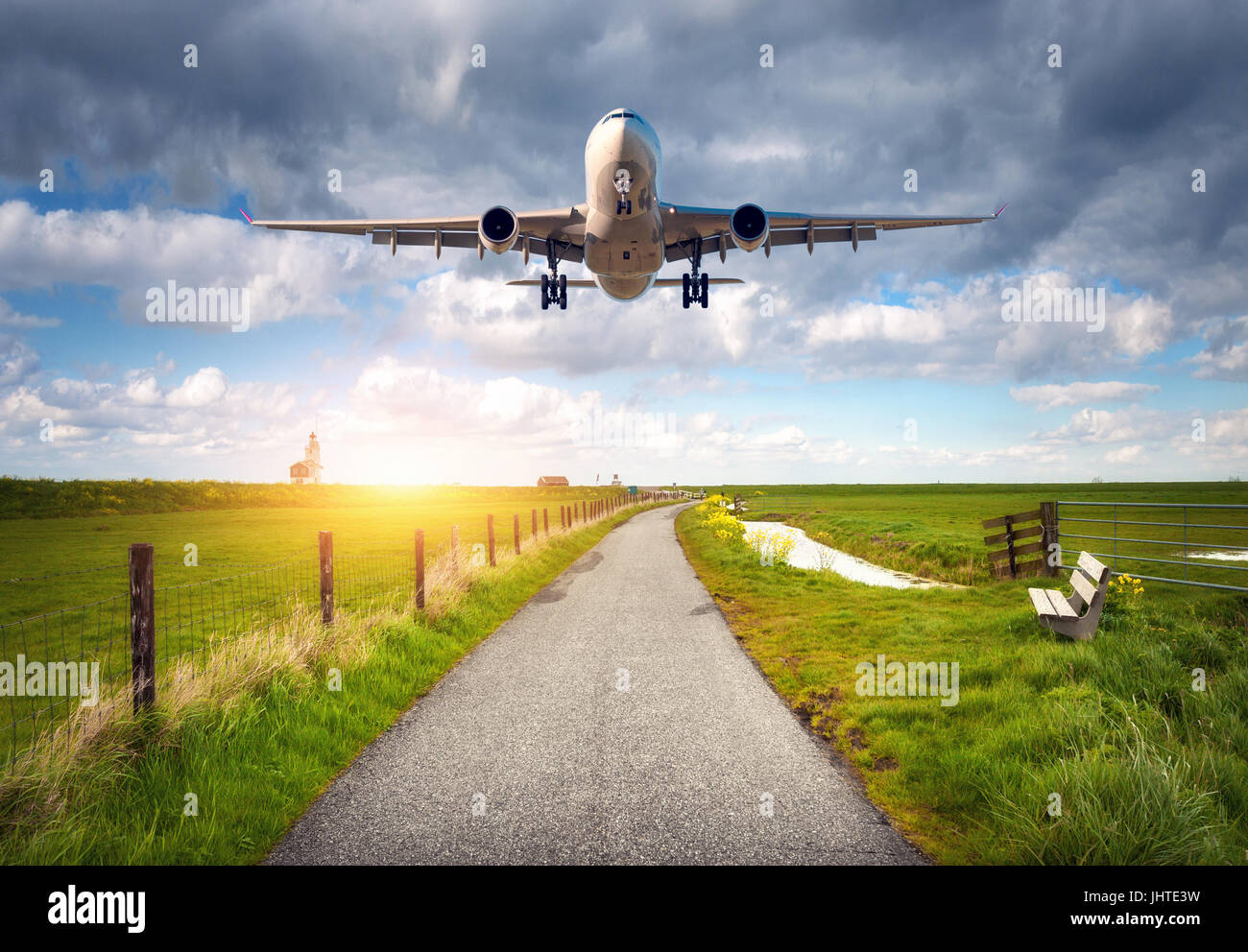 Airplane and rural road. Landscape with passenger airplane is flying ...