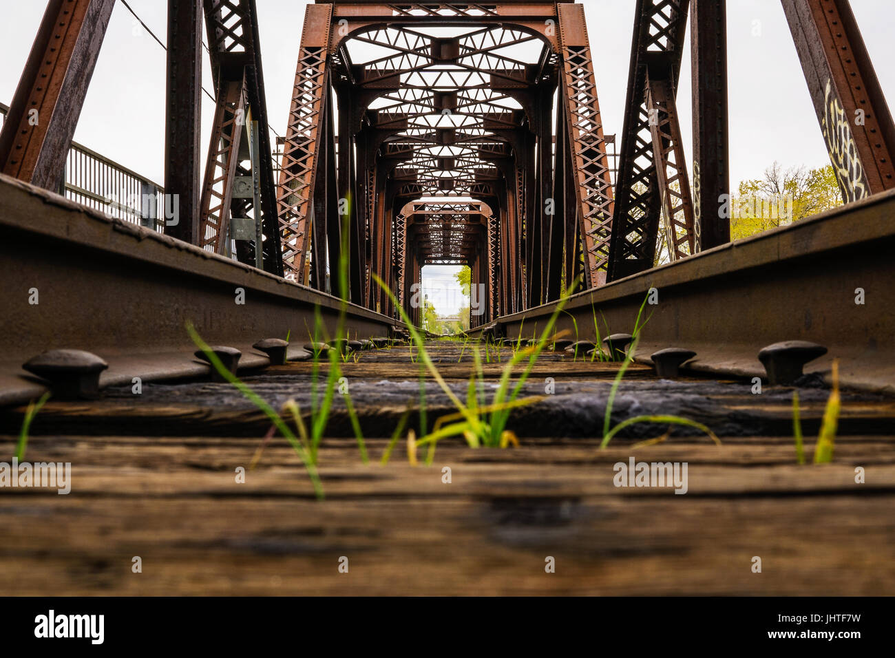 Abandoned railroad bridge, rusted with grass growing through the train ...