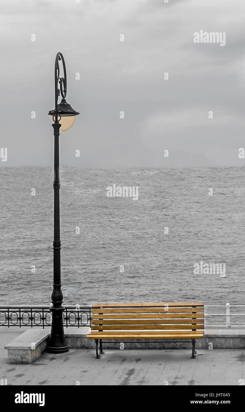 Light pole with colored bench on seafront, seaside, cloudy day, dawn ...
