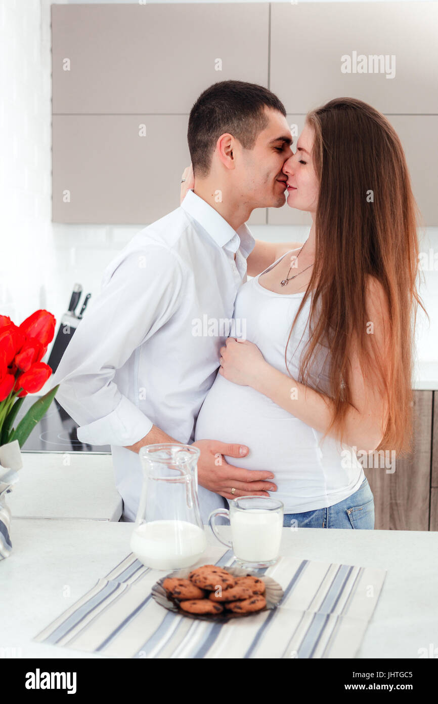 Man kissing his pregnant wife and touching his belly Stock Photo - Alamy