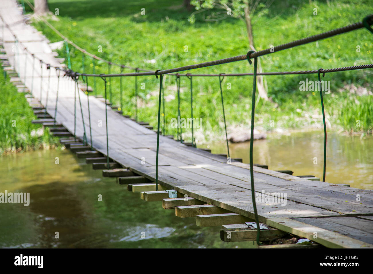 very old hanging footbridge across river. summer Stock Photo - Alamy