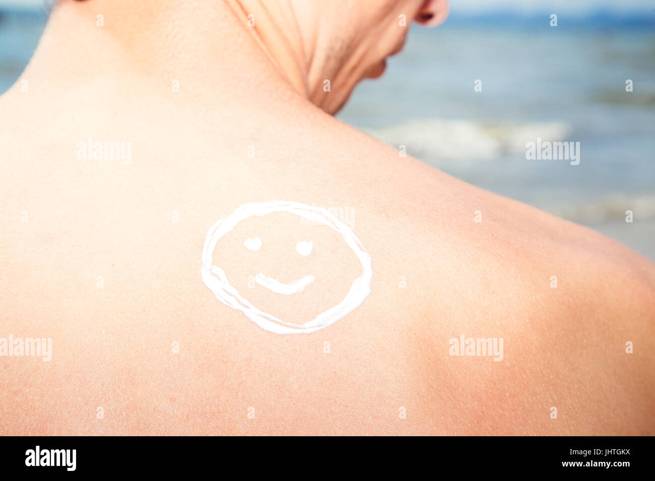 Lotion man with sunscreen smiley above sea background Stock Photo - Alamy