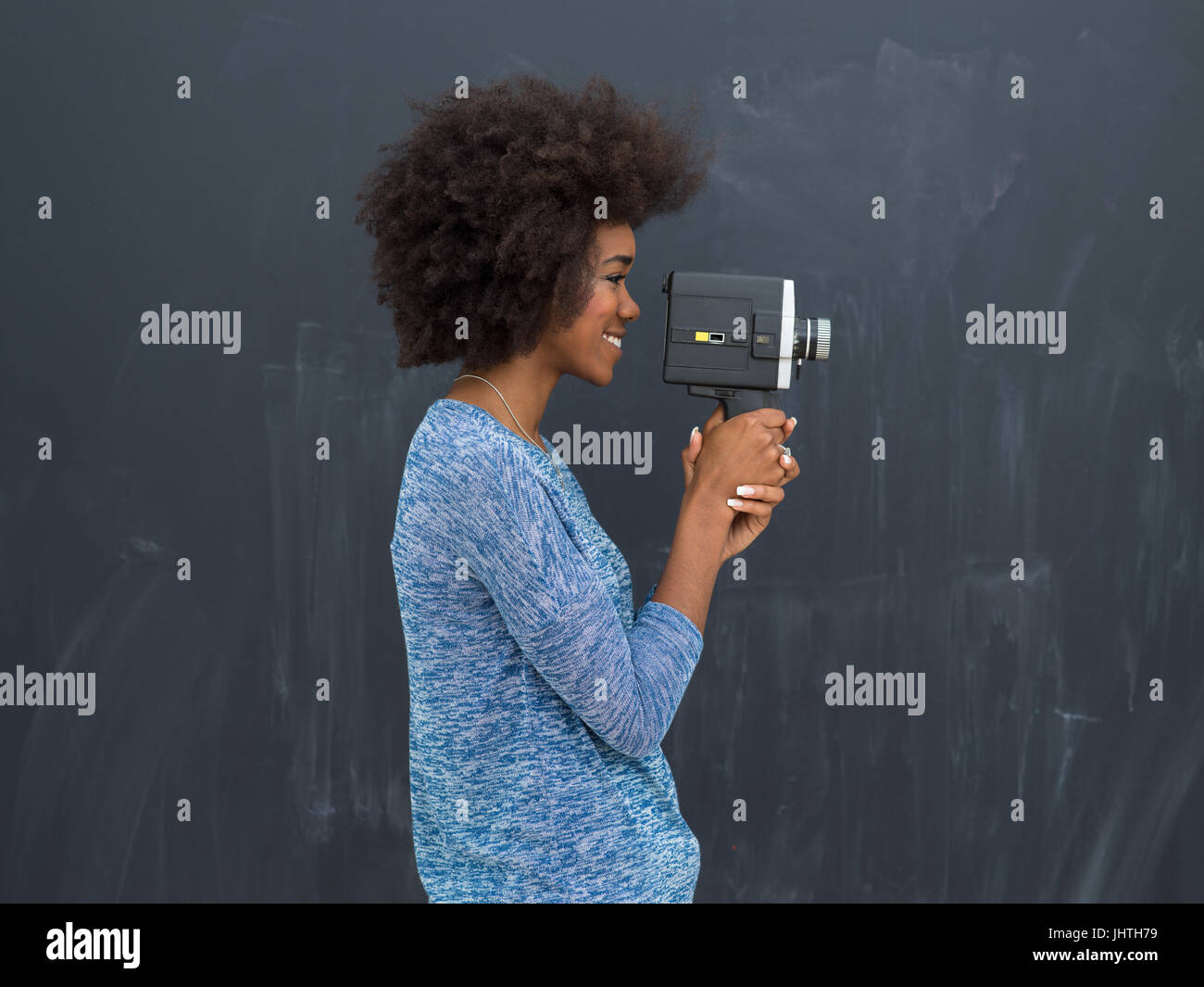 A young beautiful african american woman using a retro video camera ...