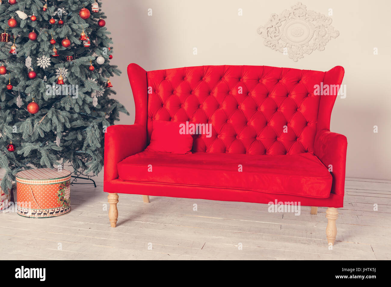 decorated Christmas tree and a red sofa in the room Stock Photo - Alamy