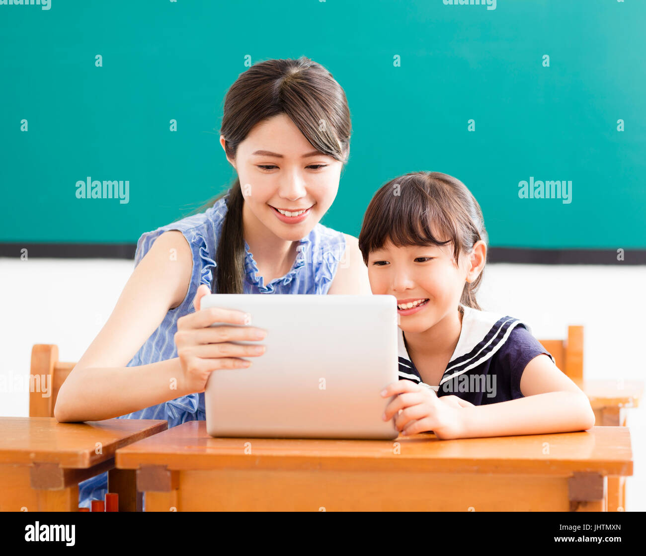 young Teacher helping child with computer lesson Stock Photo - Alamy