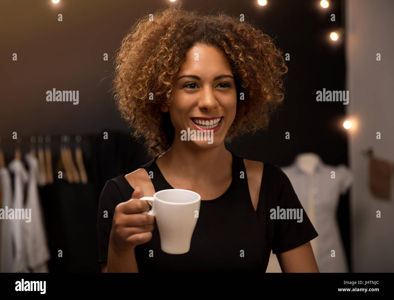 Young fashion designer on her atelier making a pause and drinking ...