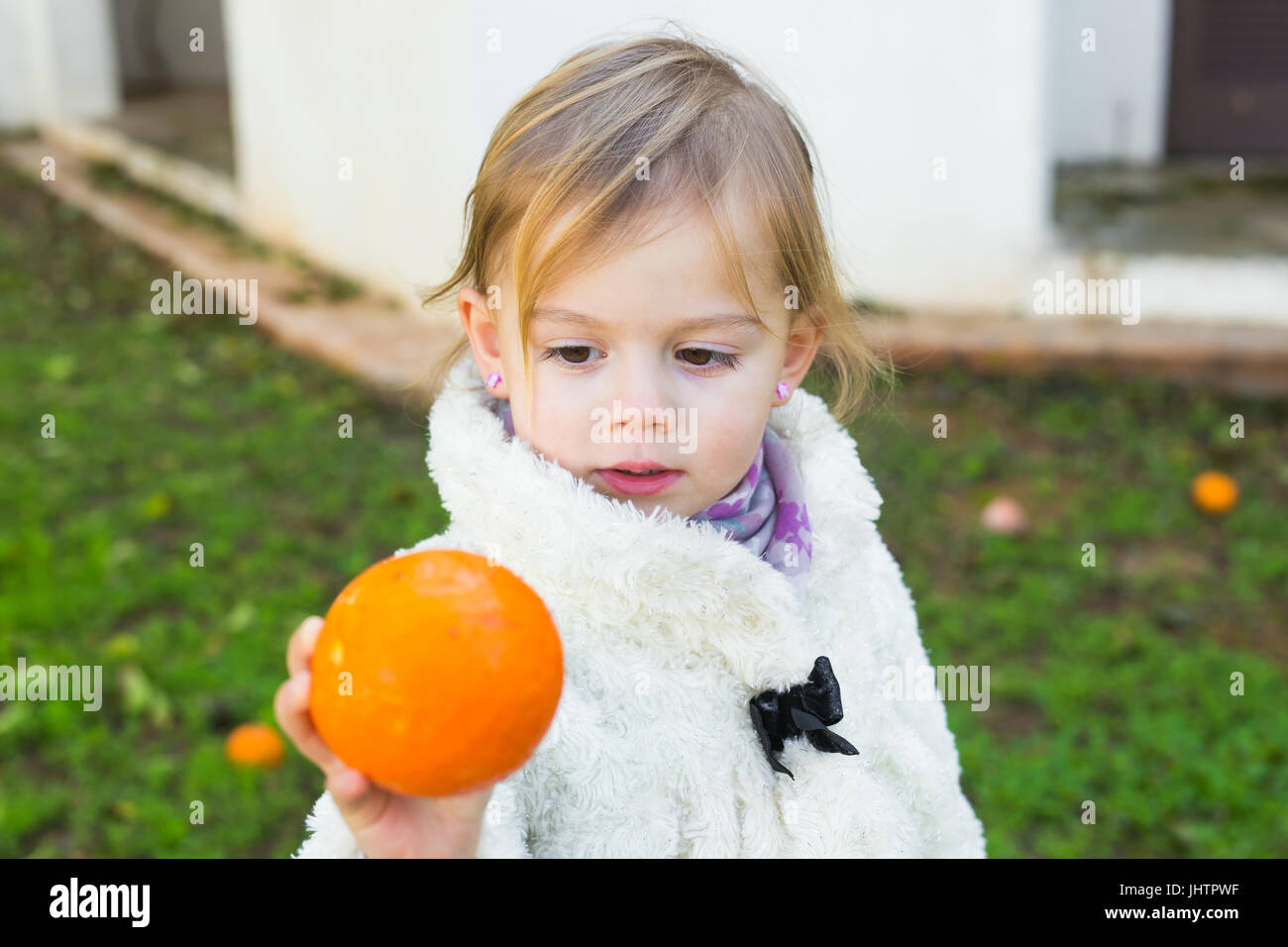 Cute baby girl showing orange Stock Photo - Alamy