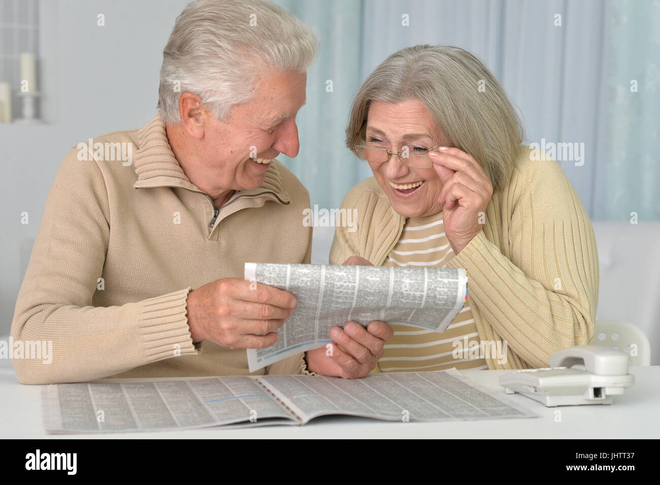 Happy senior couple reading newspaper Stock Photo - Alamy