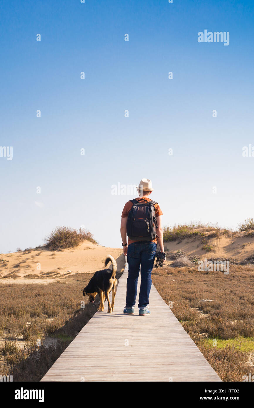 View from behind of a man walking with his dog on a road leading ...