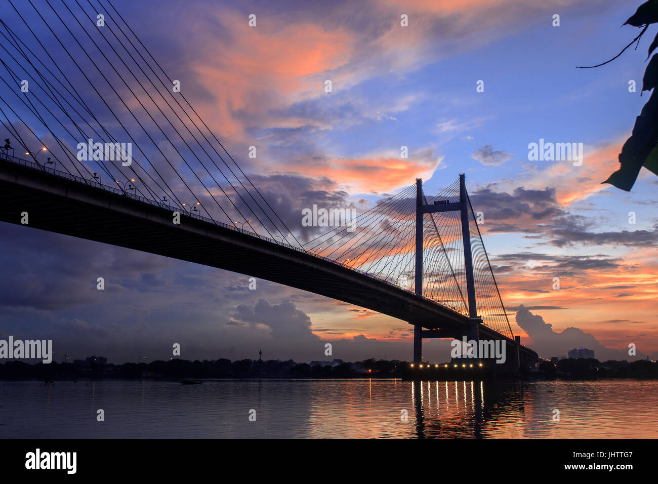 Silhouette of Vidyasagar Setu bridge at twilight with a wooden boat on ...