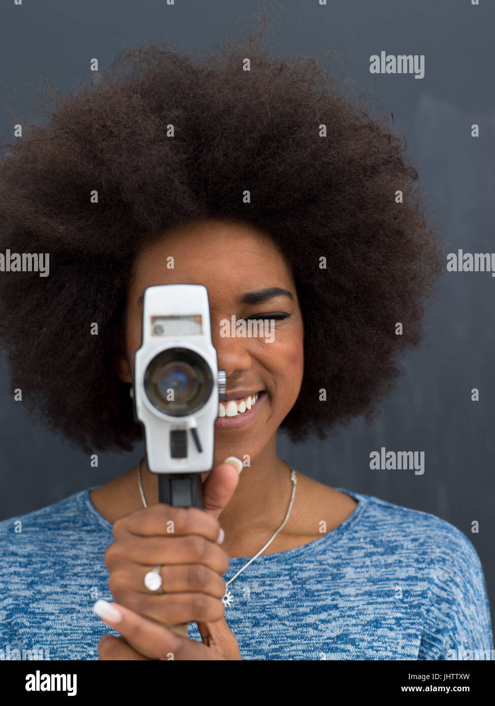 A young beautiful african american woman using a retro video camera ...