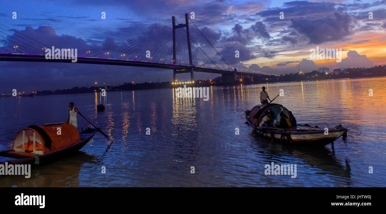 Silhouette of Vidyasagar Setu bridge at twilight with a wooden boat on ...
