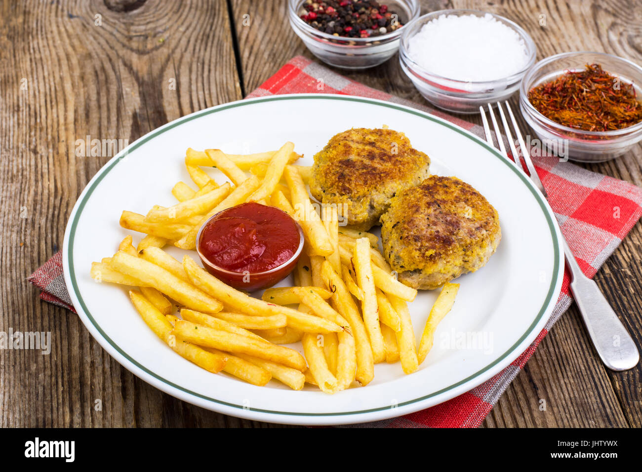 White plate with French fries and meat cutlets on wooden table. Studio ...