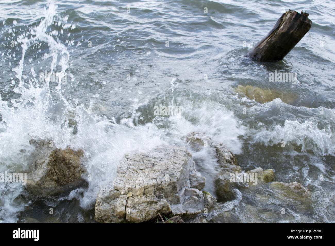 Waves breaking rocks on the shore of the lake Stock Photo - Alamy