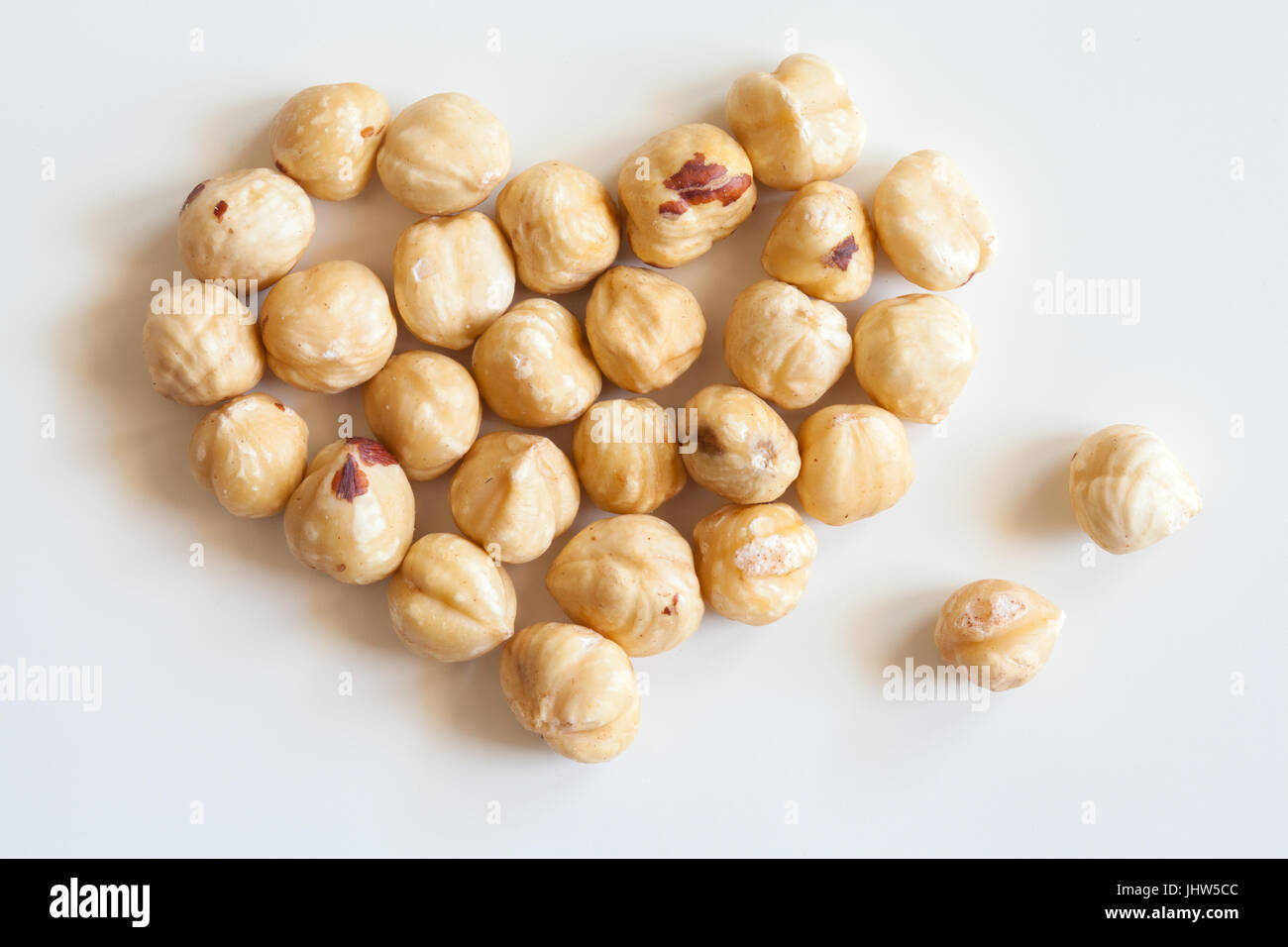 Heart shaped bunch of roasted hazelnuts on white background Stock Photo ...