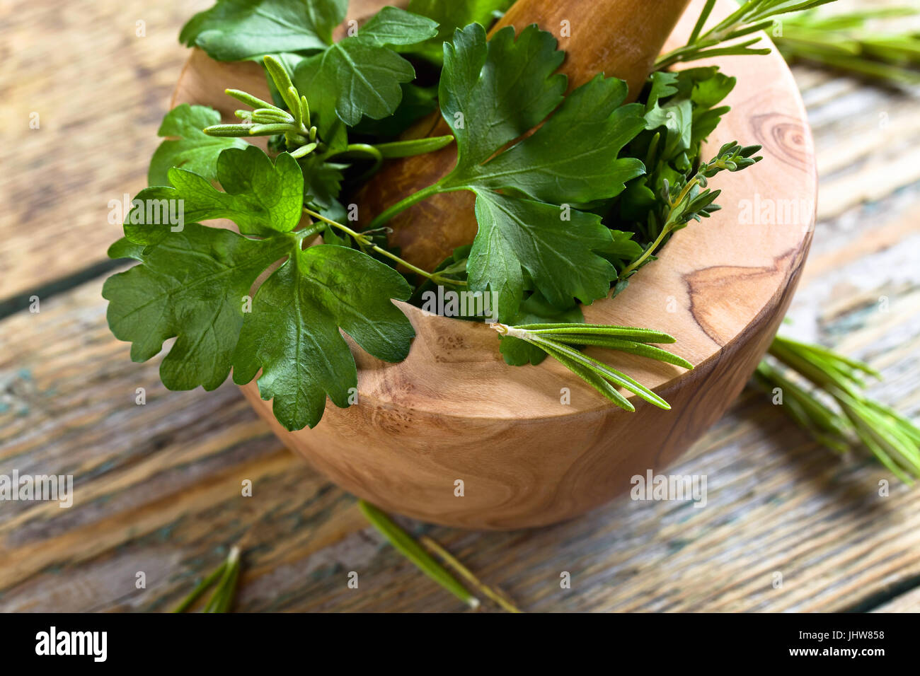 Different herbs on a old wooden table . Wooden mortar with rosemary ...