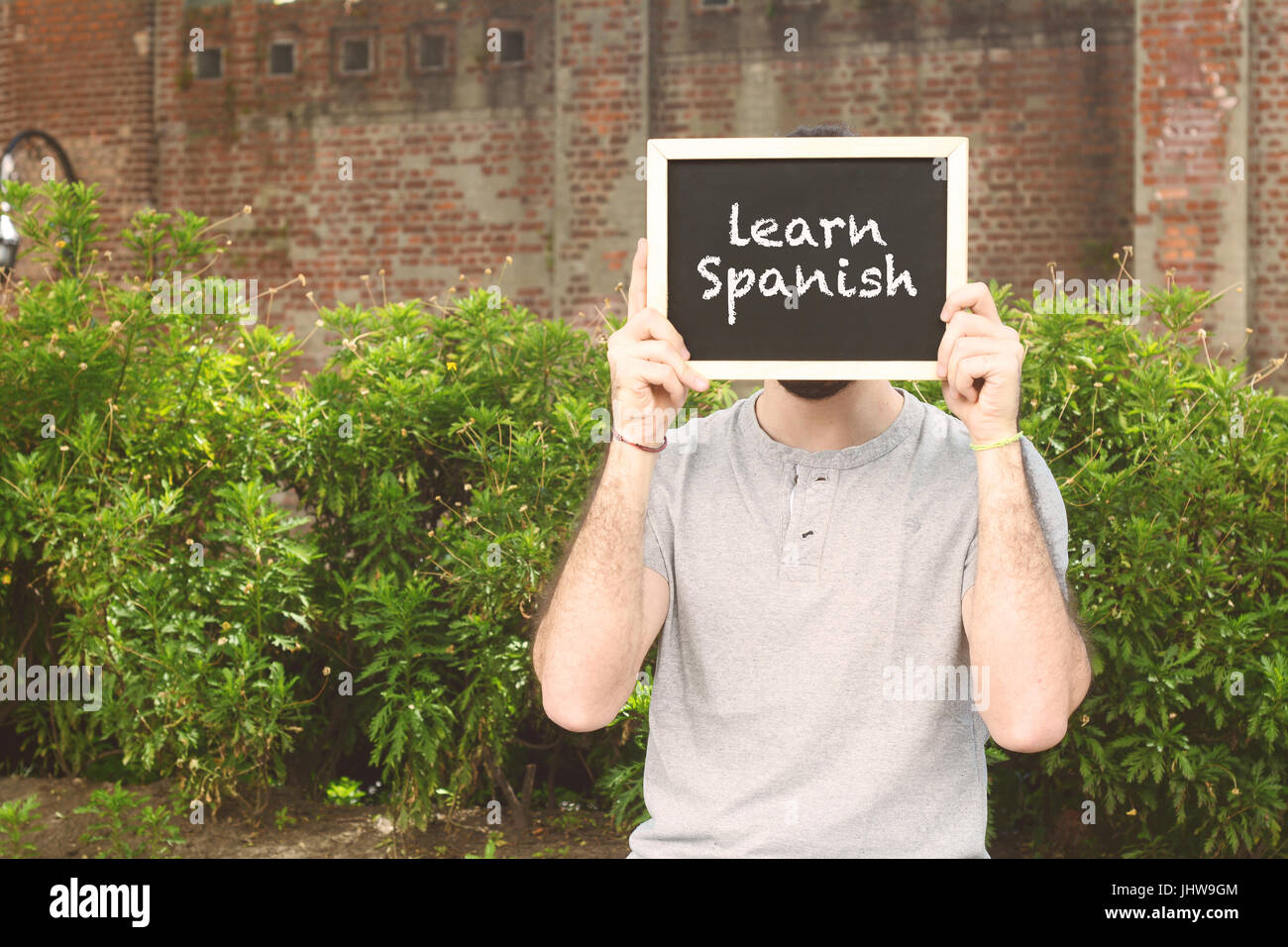 Portrait of handsome young man holding chalkboard with text "learn ...