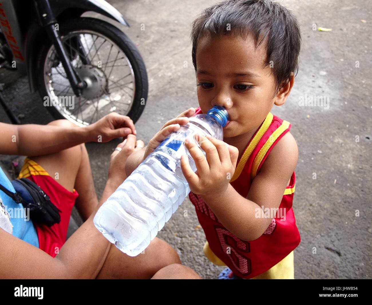 CAINTA CITY, PHILIPPINES - JULY 12, 2017: A boy drinks from a bottle ...