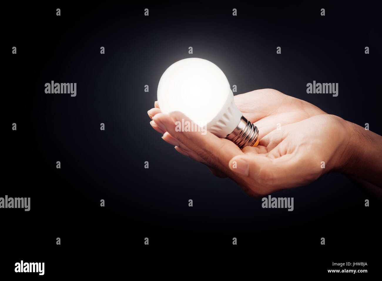 light bulb hold in hand on black background Stock Photo - Alamy