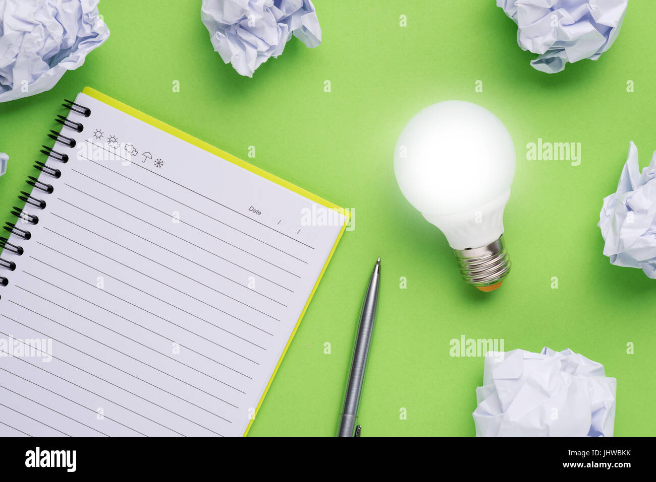 Note book and light bulb on green background Stock Photo - Alamy