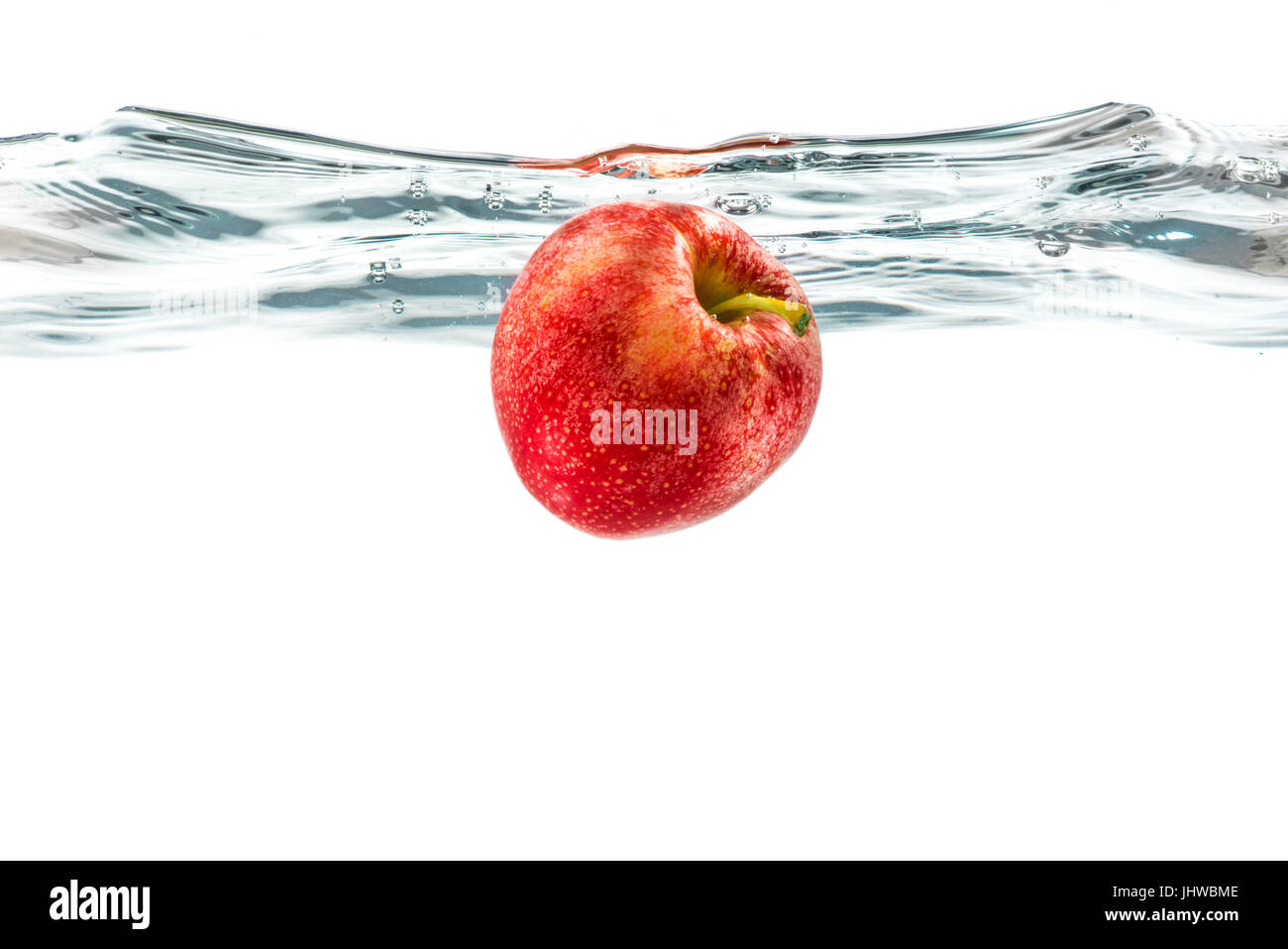 Red apple dropped into the water with water splash on a white ...