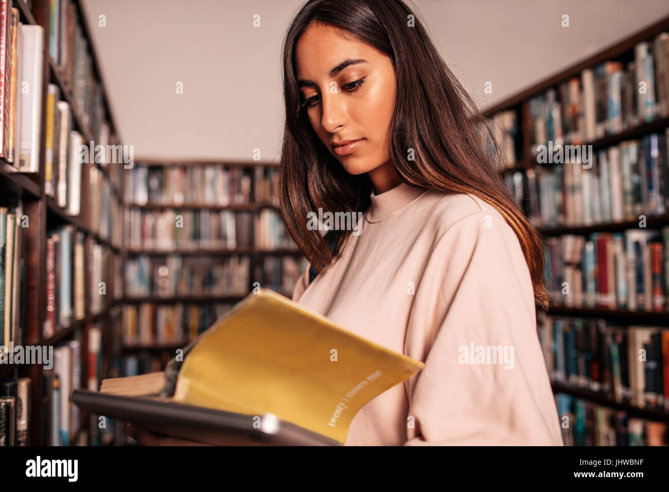 University student reading book with tablet in the library. Young ...