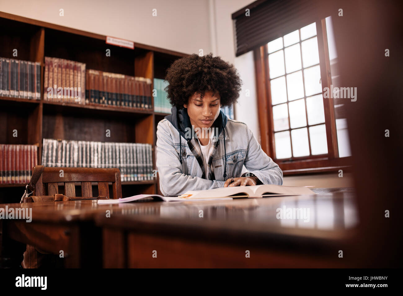 African college student reading book in library. Young student sitting ...